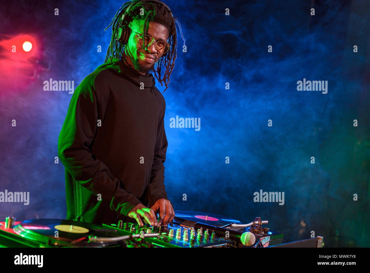 professional african american DJ in headphones with sound mixer in ...