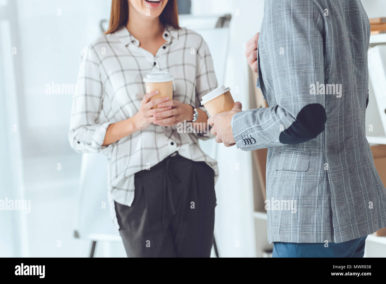 cropped image of male and female colleagues having coffee break in ...