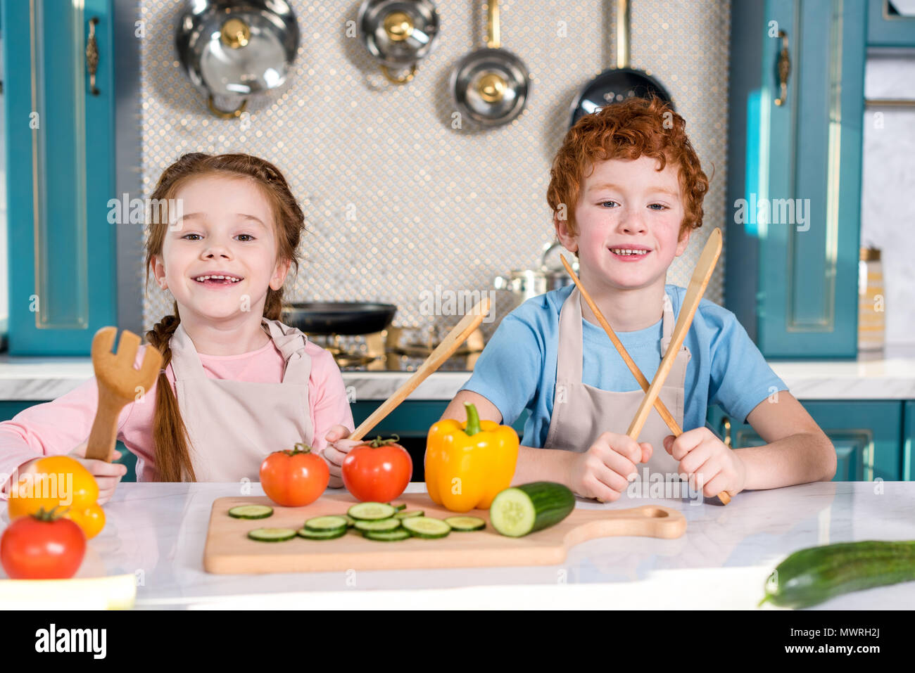 adorable children holding wooden utensils and smiling at camera while ...