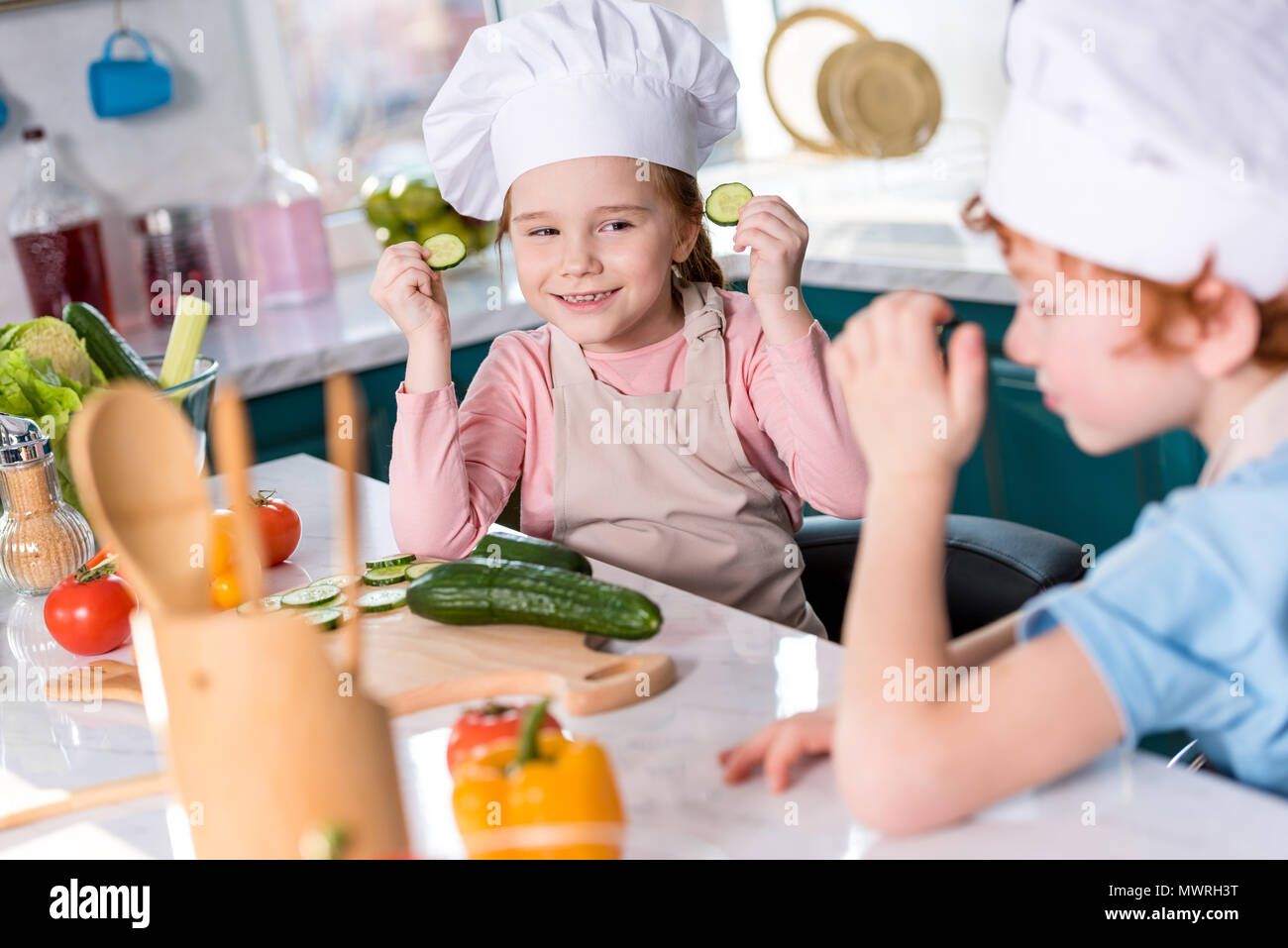 cute little children in chef hats having fun while cooking together in ...