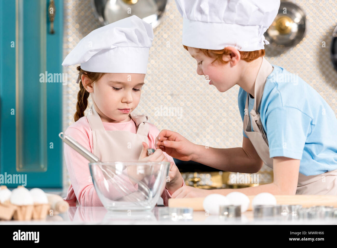 beautiful little children in chef hats and aprons cooking together in ...