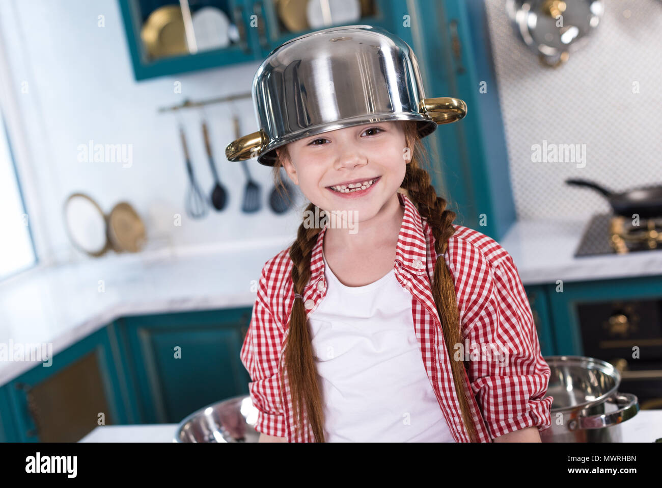 adorable little child with pan on head smiling at camera in kitchen ...