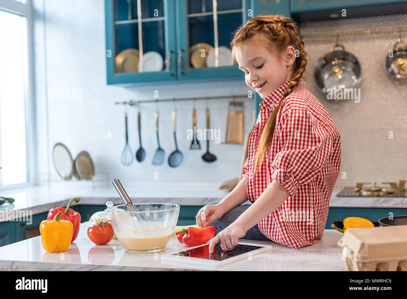 cute smiling child using digital tablet while cooking in kitchen Stock ...