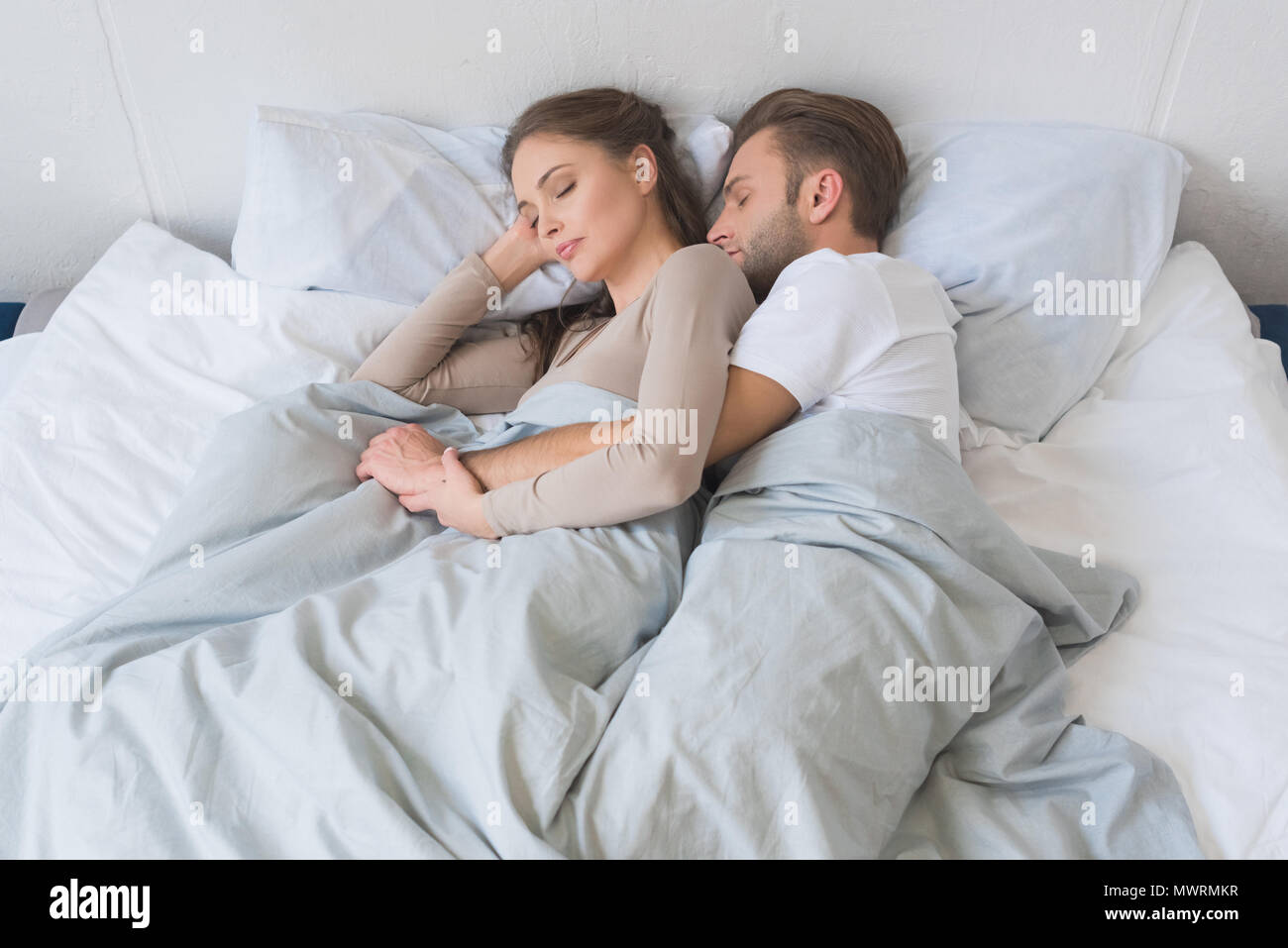 Young couple sleeping peacefully and hugging in bed Stock Photo - Alamy
