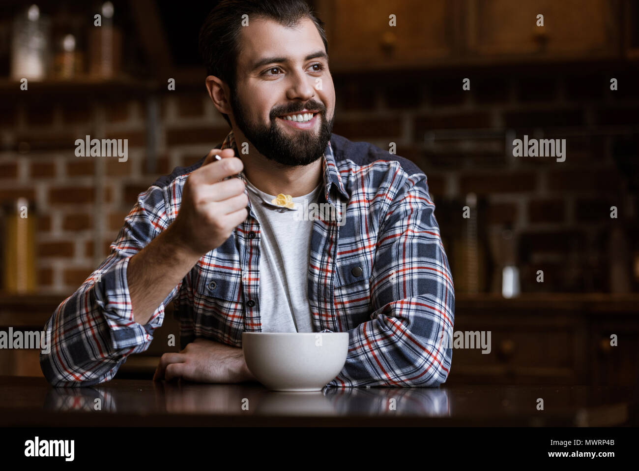 smiling man eating snacks with milk at kitchen Stock Photo - Alamy