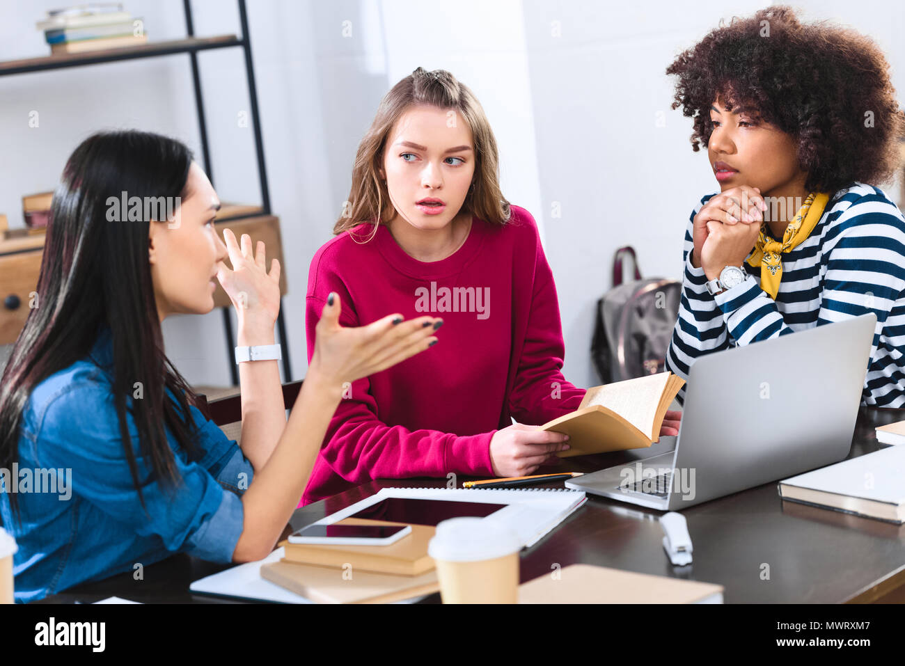 multiracial students having discussion while doing homework together ...