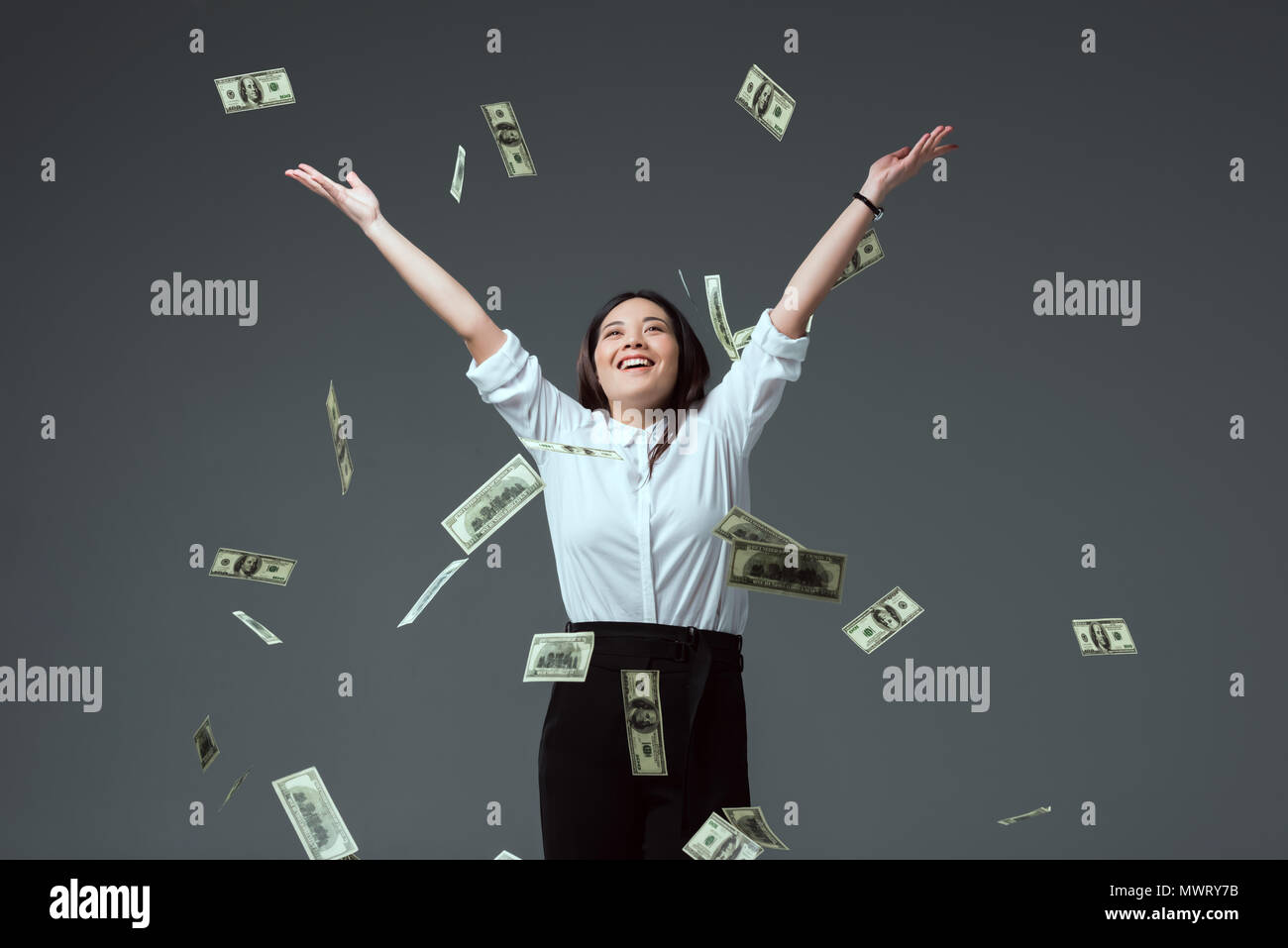 happy young asian woman throwing dollar banknotes isolated on grey ...
