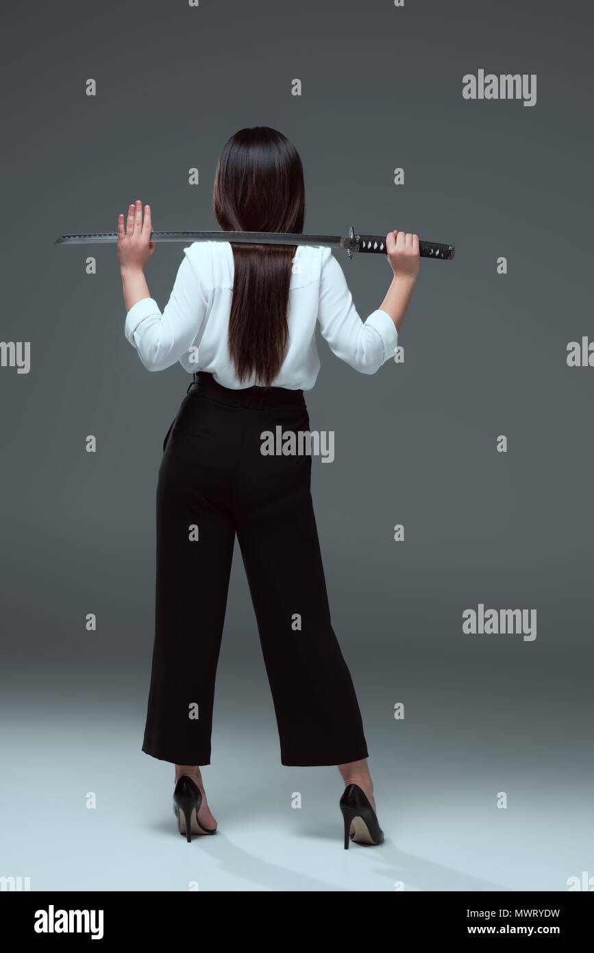 back view of woman holding katana on shoulders on grey Stock Photo - Alamy