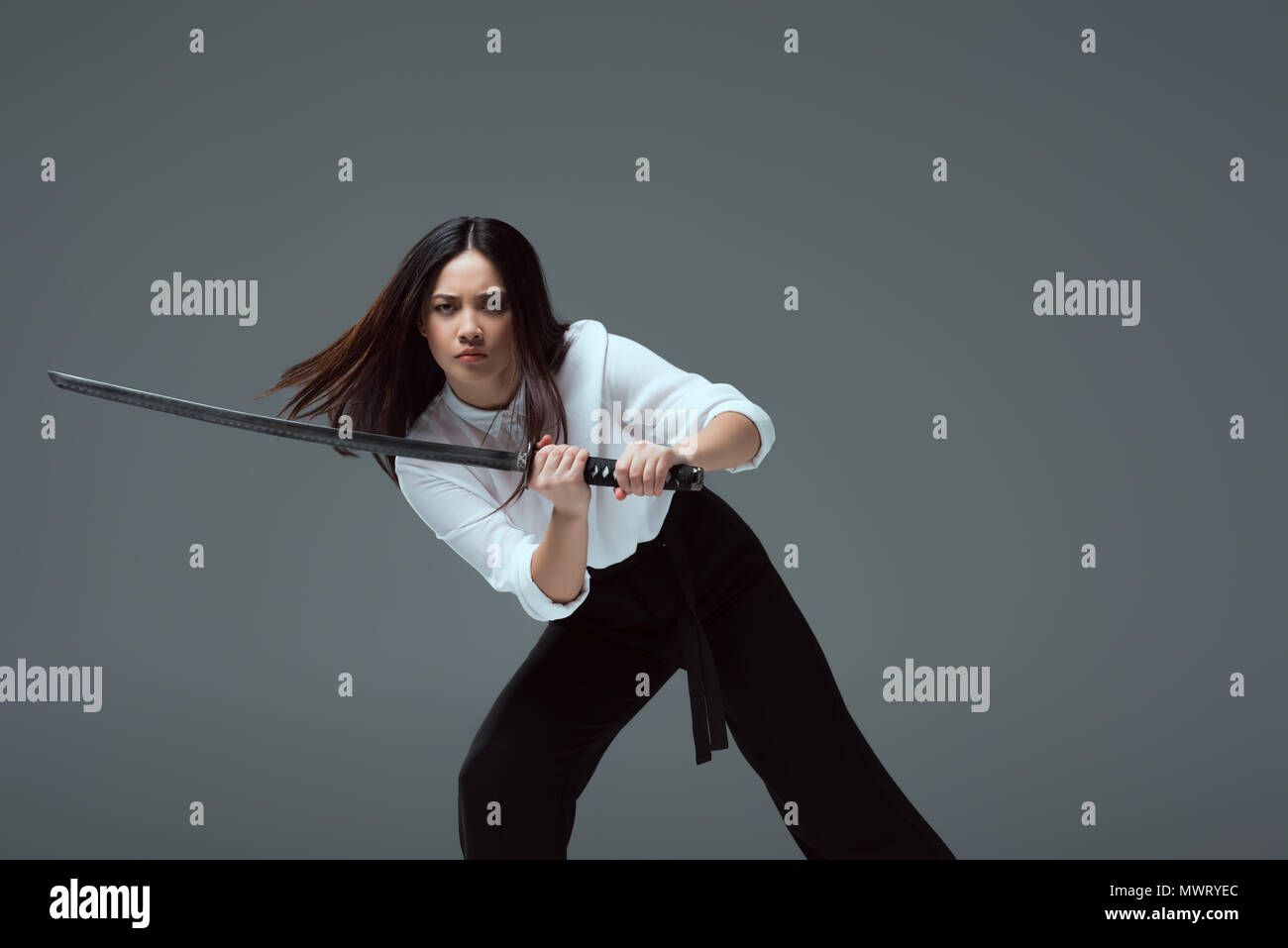 young asian woman fighting with katana sword isolated on grey Stock ...