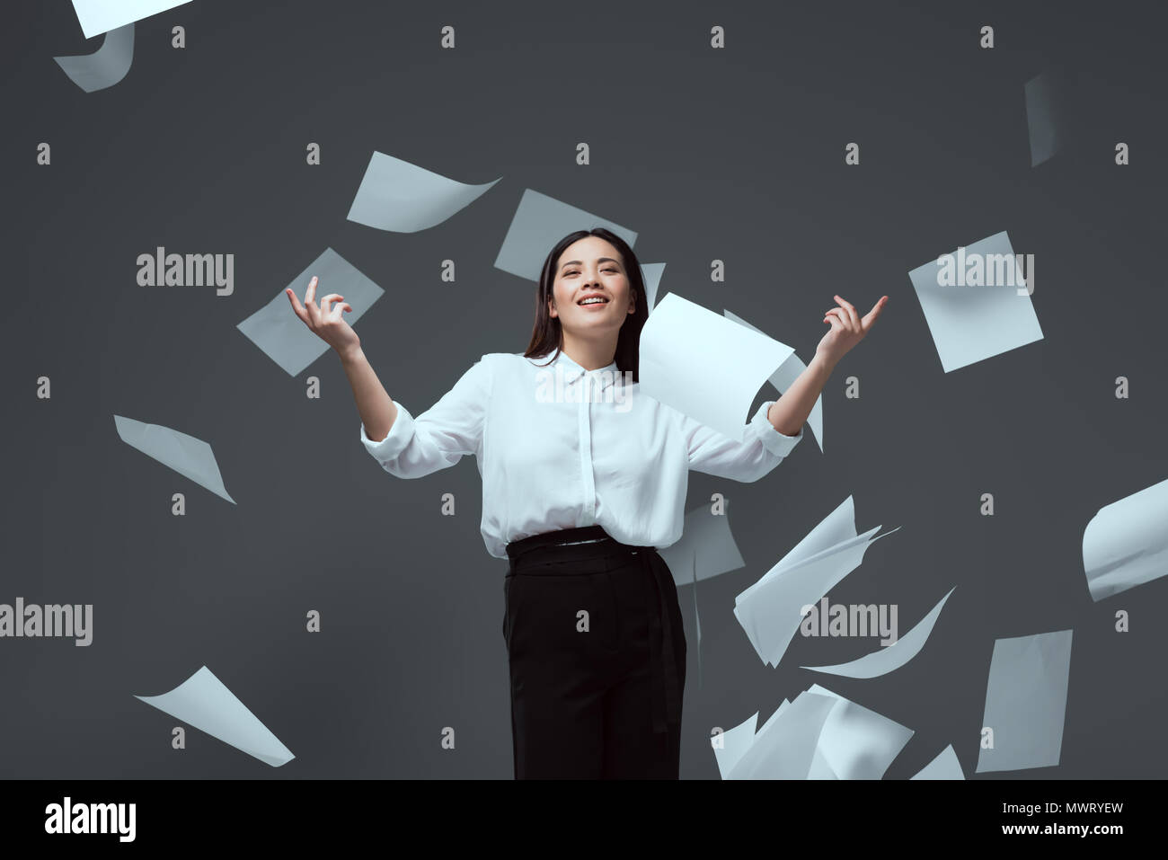 smiling young businesswoman throwing papers isolated on grey Stock ...