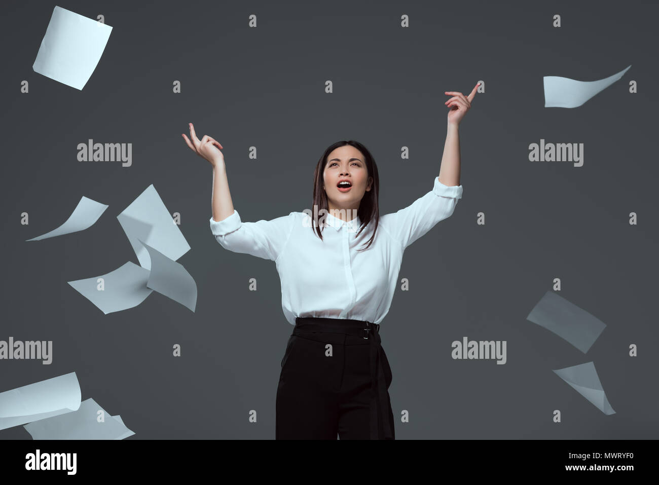 emotional young businesswoman throwing papers isolated on grey Stock ...