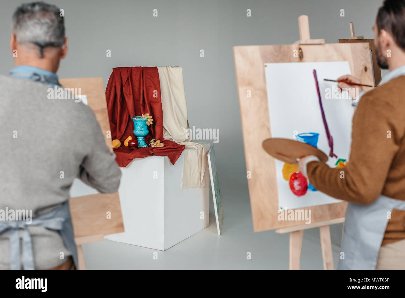 back view of two men painting still life on easels at art class Stock ...