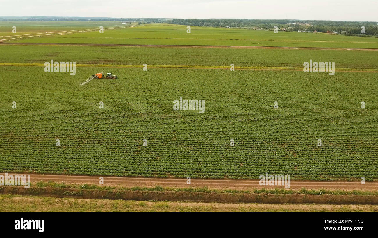 Aerial view tractor spraying the chemicals on the large green field ...
