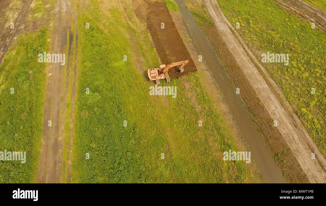 Excavator is digging an irrigation canal. Aerial view:Excavator digging ...