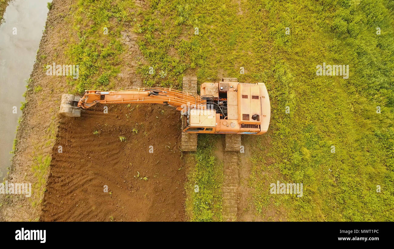 Excavator is digging an irrigation canal. Aerial view:Excavator digging ...