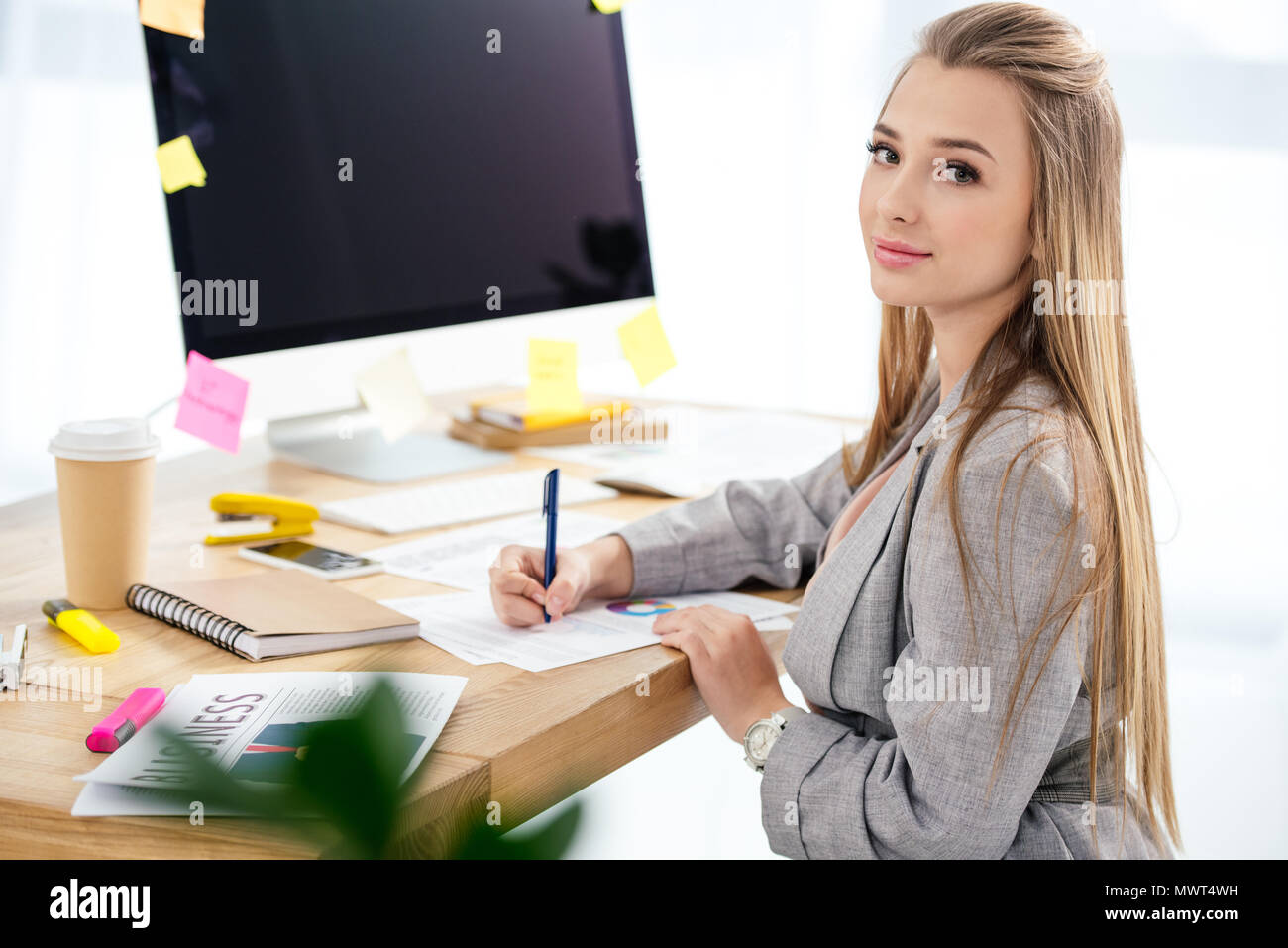side view of female marketing manager looking at camera while doing ...