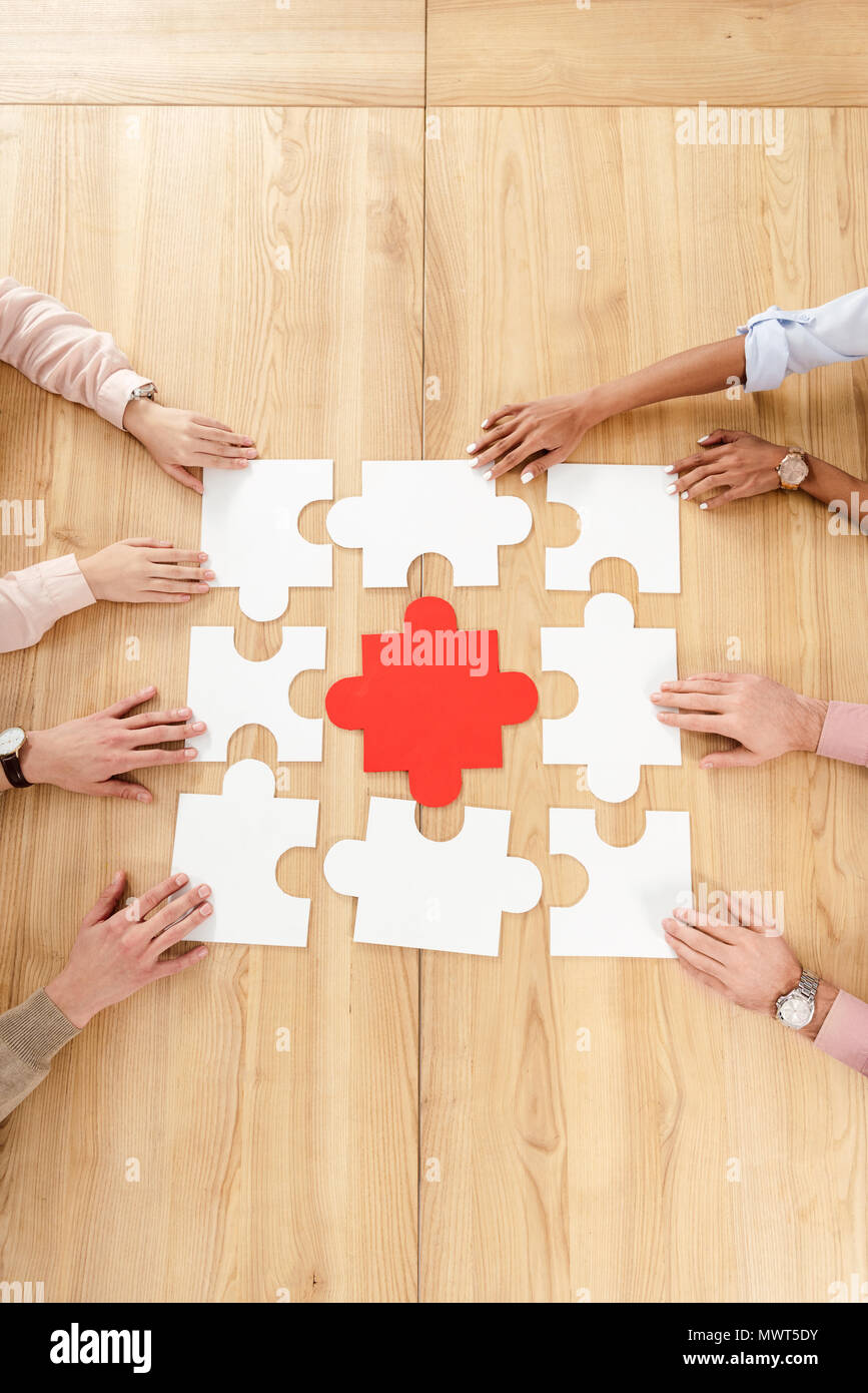 overhead view of multiracial business people collecting blank puzzles ...