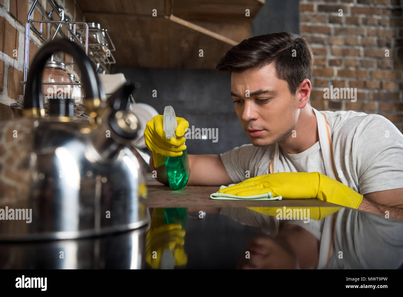serious handsome man cleaning kitchen with spray bottle and rag Stock ...