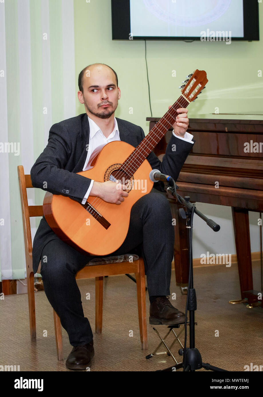 Young guitarist sitting on the stage with a guitar in his hands Stock ...
