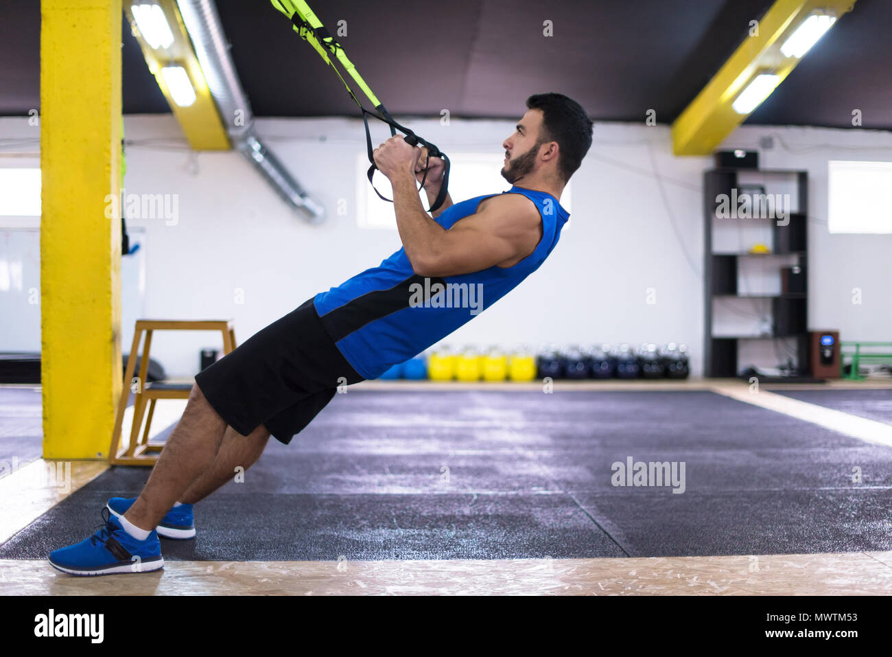 young athlete man working out pull ups with gymnastic rings at the ...