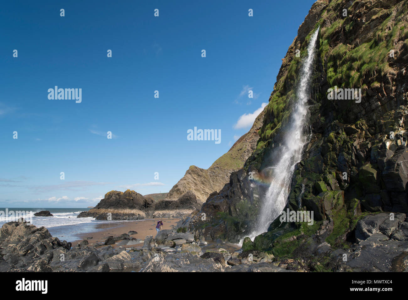 Waterfall cascading over a sea cliff at Tresaith, Ceredigion, West ...