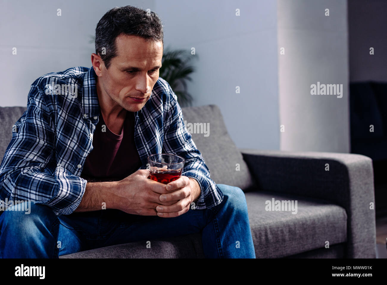 side view of man with glass of alcohol sitting on sofa at home Stock ...