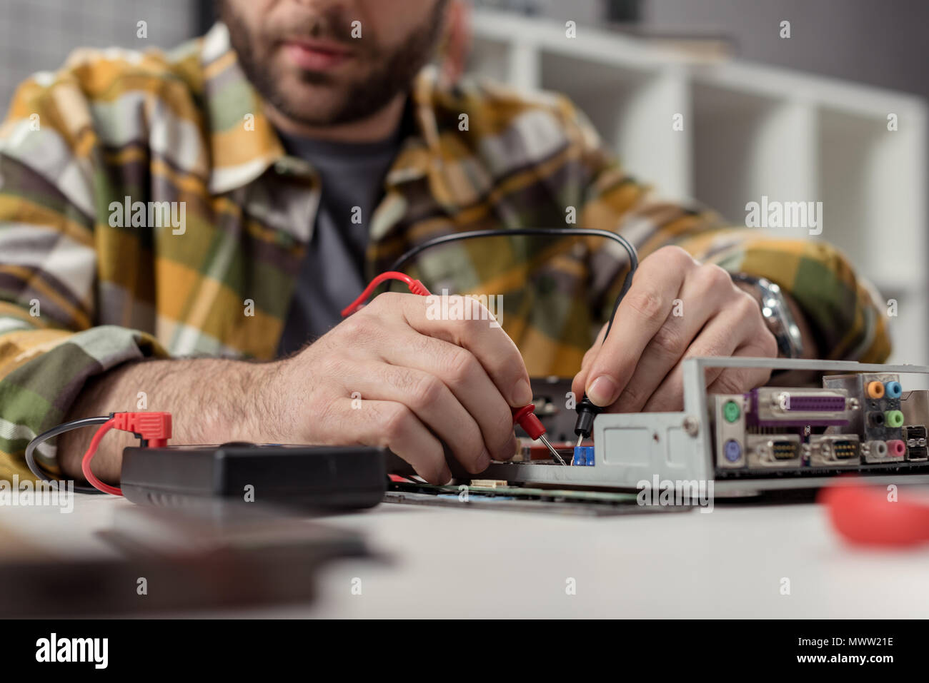 cropped image of man using multimeter while fixing broken computer ...