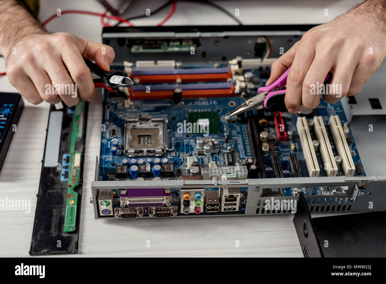 cropped image of hands with tongs fixing motherboard of pc Stock Photo ...