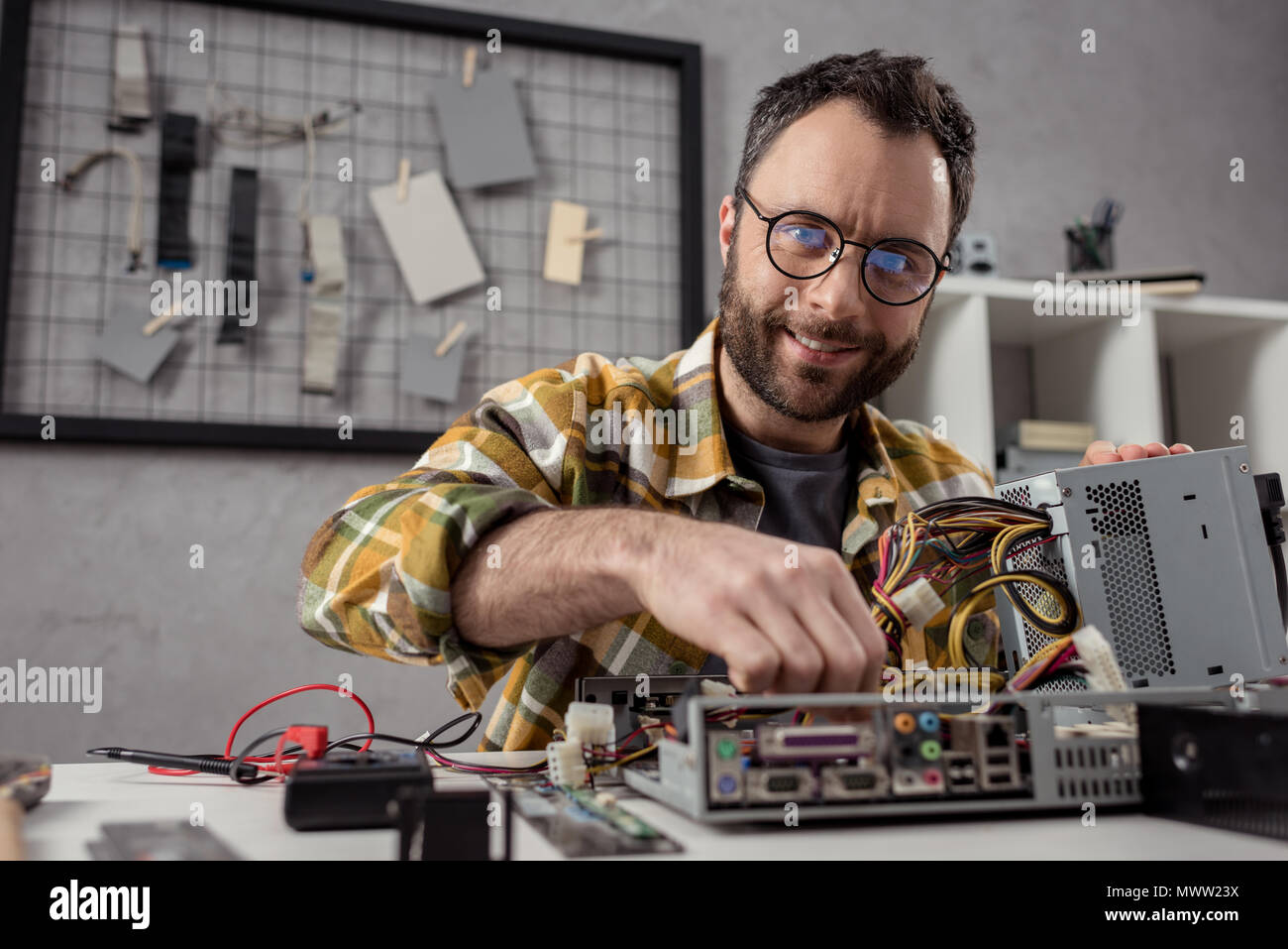 smiling man adjusting details while fixing computer Stock Photo - Alamy