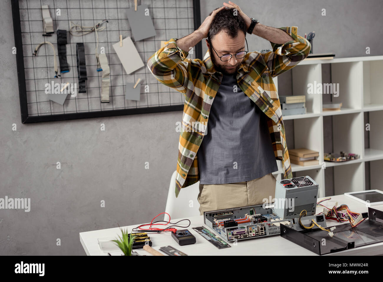 tired repairman looking down on broken computer Stock Photo - Alamy