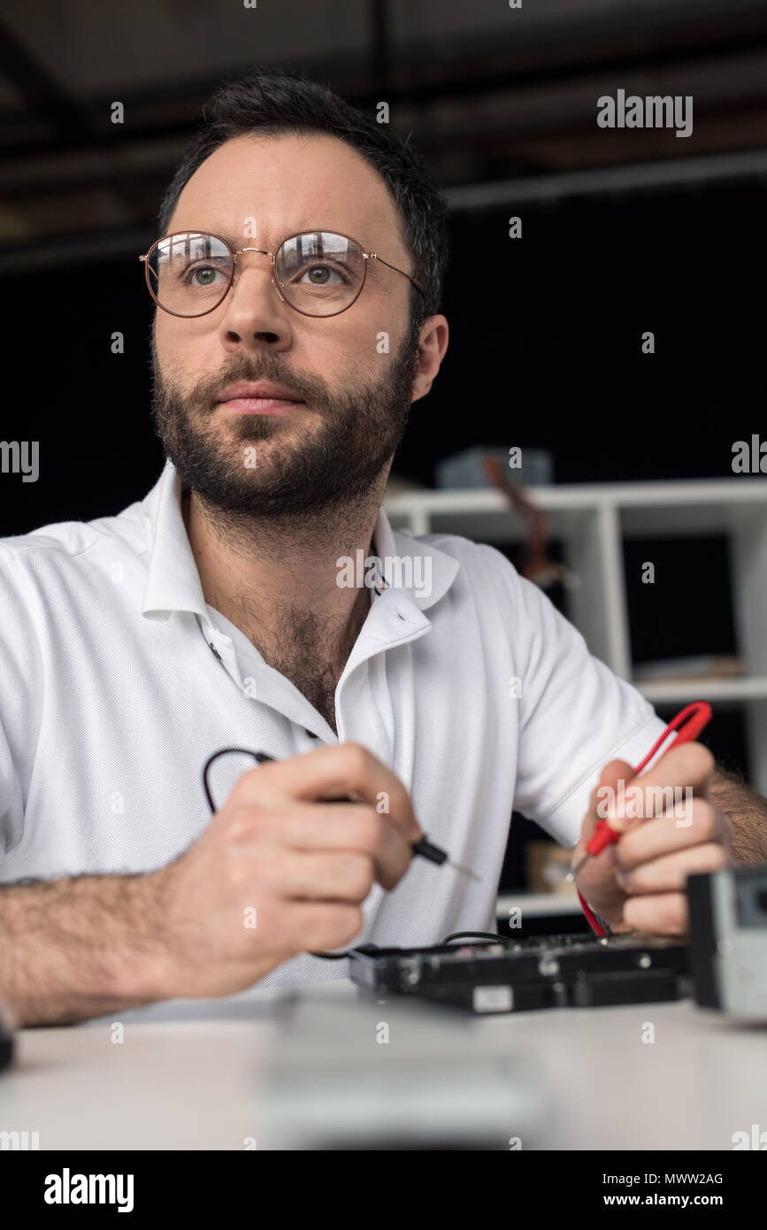 repairman using multimeter while testing hard disk drive and looking ...