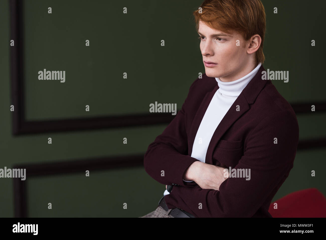 Side view of male model in jacket sitting on couch Stock Photo - Alamy