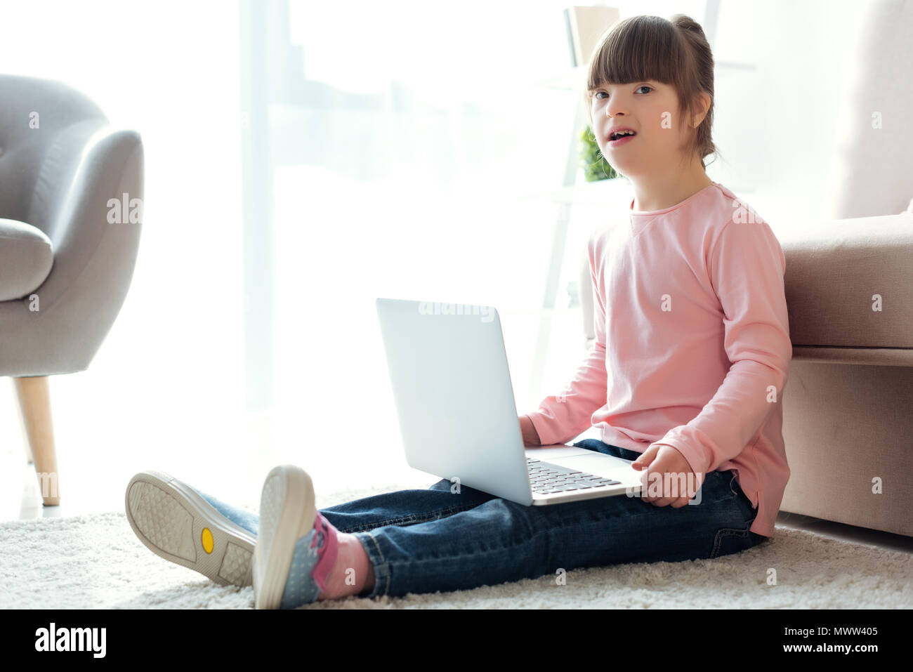 Child with down syndrome using laptop while sitting on the floor Stock ...