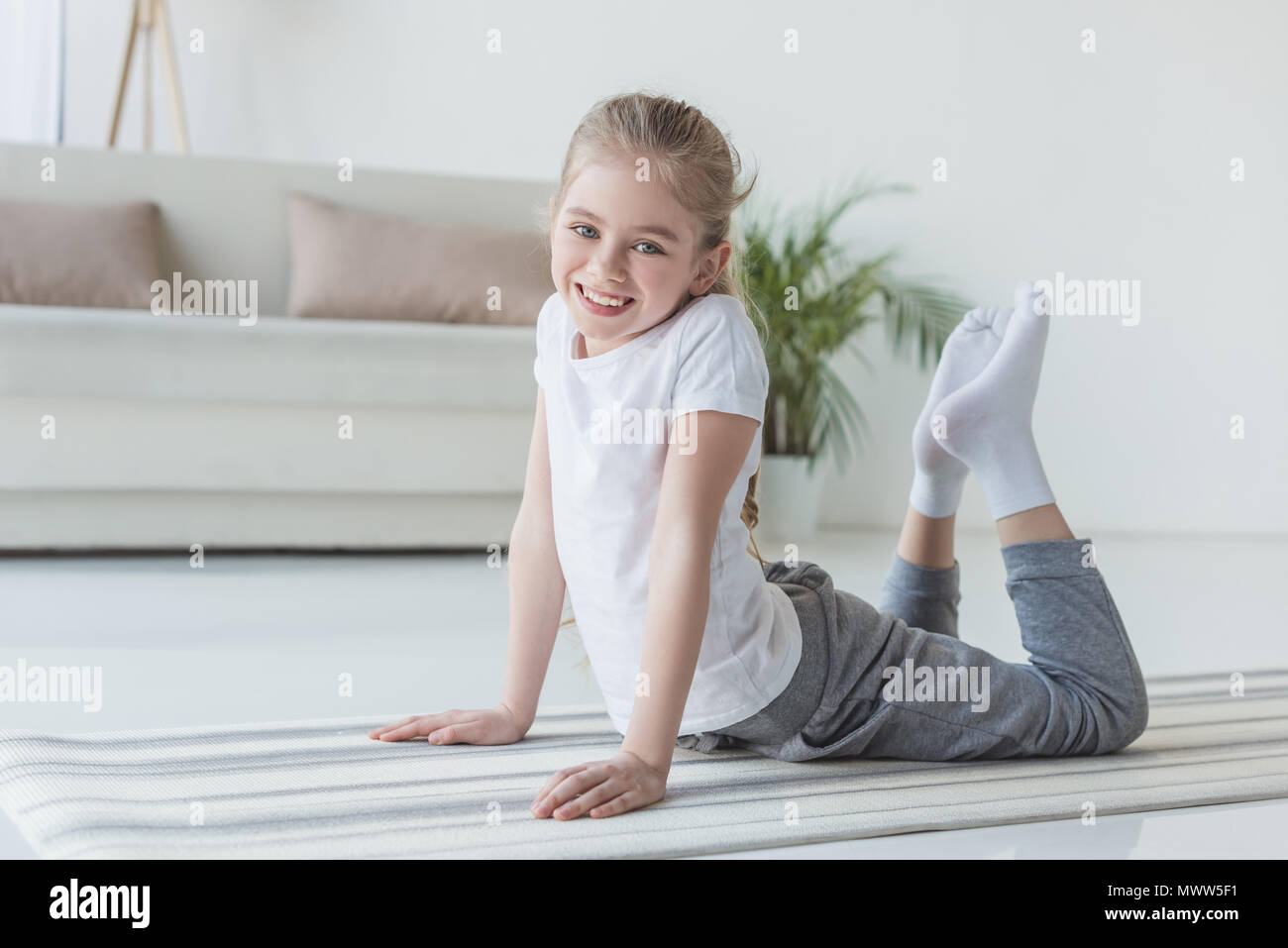 happy little child doing backbend on yoga mat and looking at camera ...