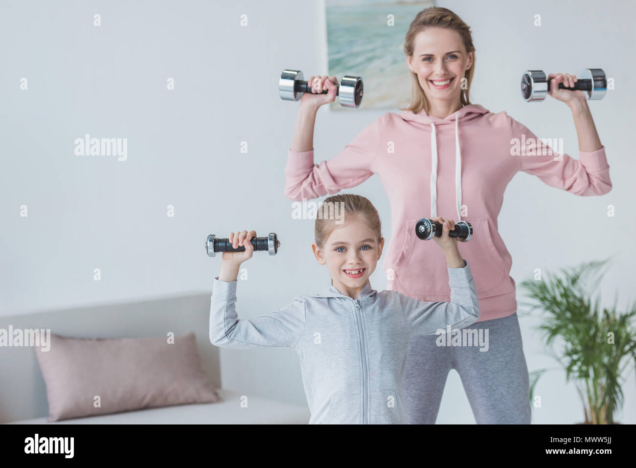 fit mother and daughter working out with dumbbells at home Stock Photo ...