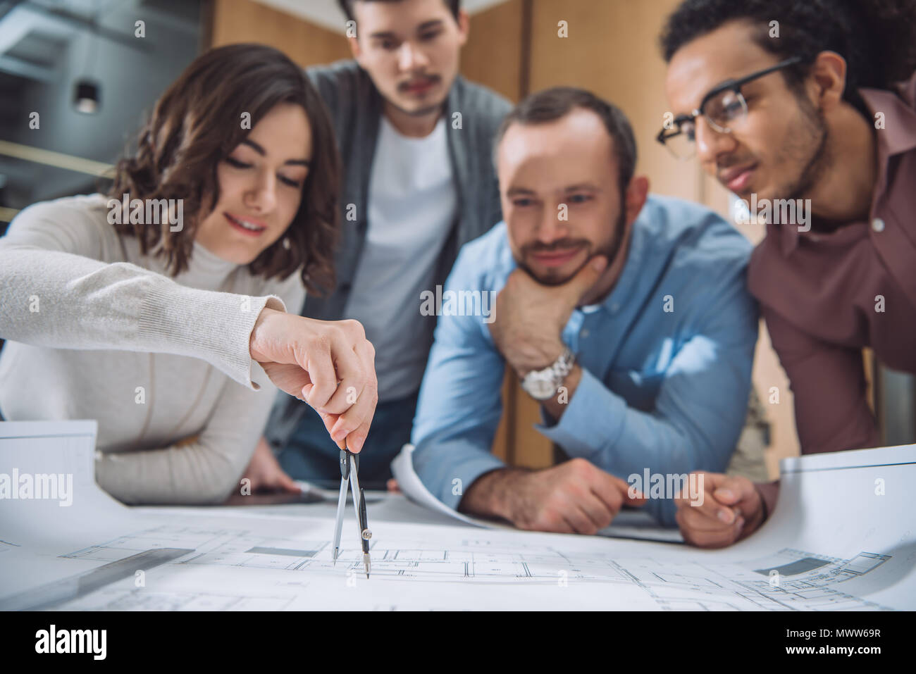 close-up shot of group of architects drawing building plan together at ...