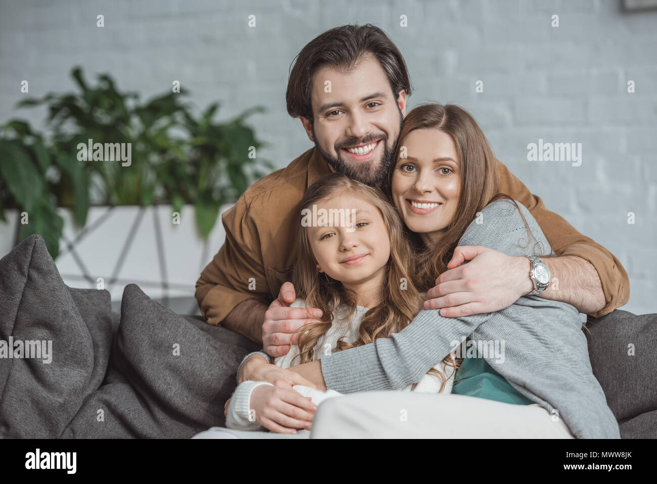 happy parents and daughter hugging and looking at camera Stock Photo ...