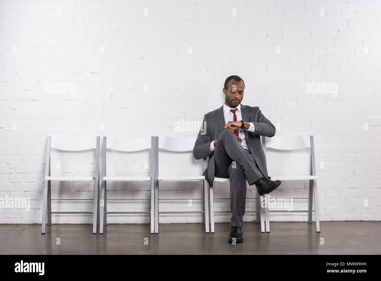 african american businessman checking time while waiting for job ...