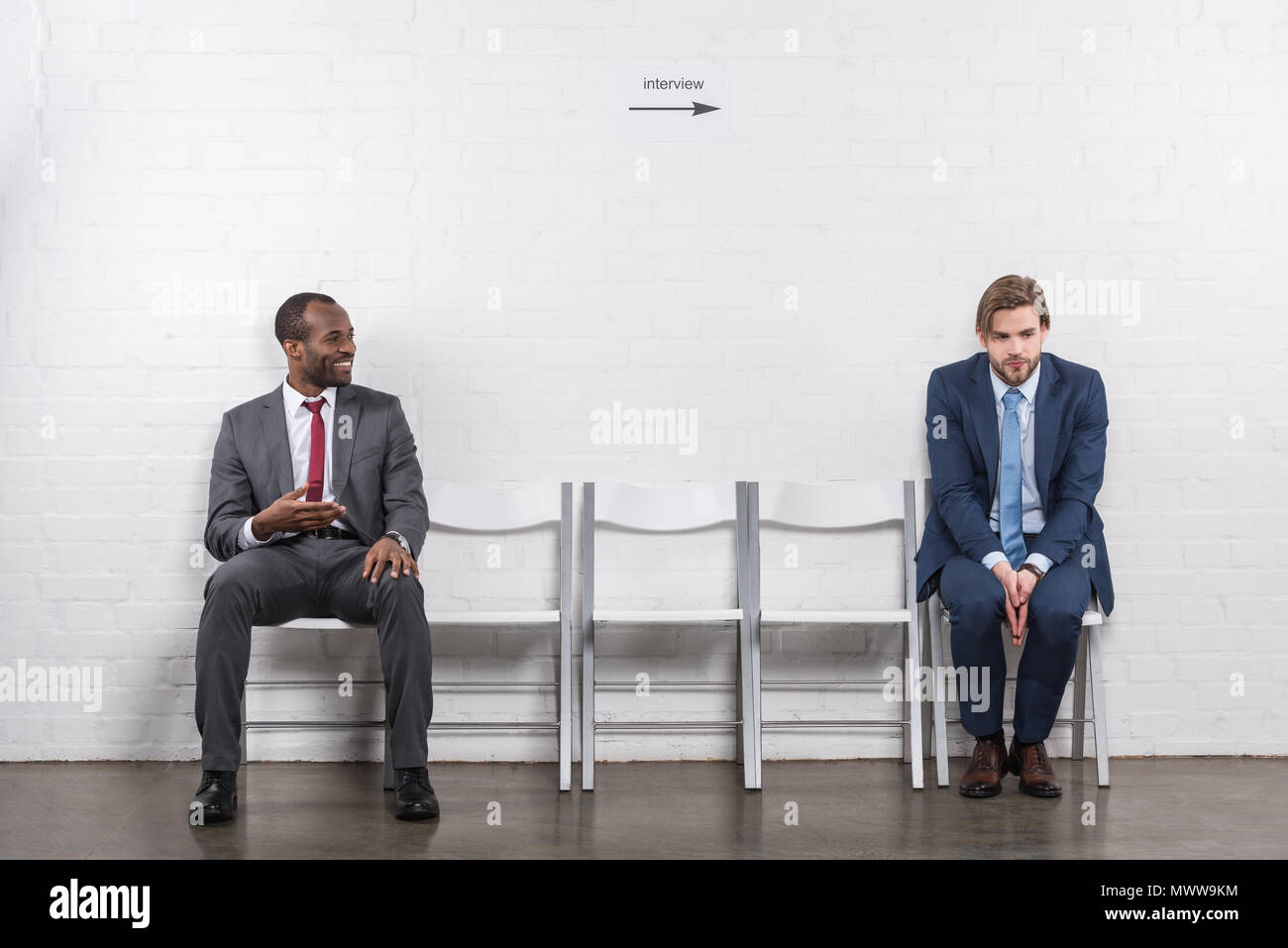 smiling african american businessman looking at scared colleague while ...