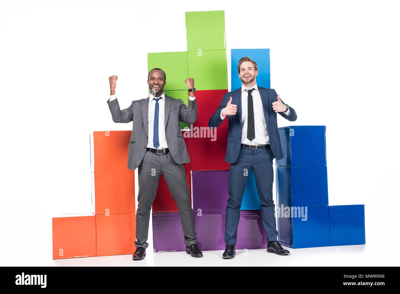 happy multiethnic businessmen standing near colorful blocks isolated on ...