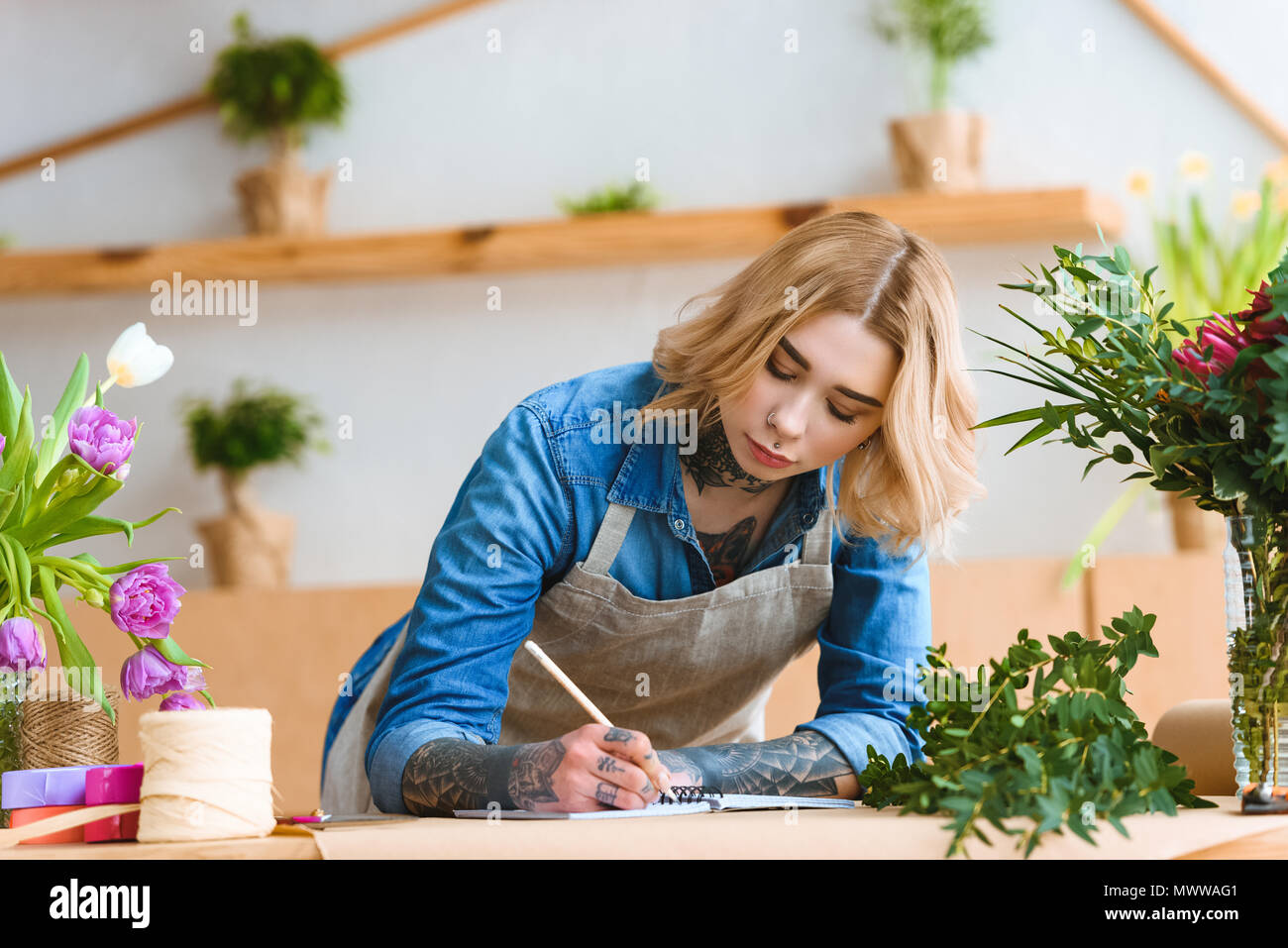beautiful young female florist taking notes at workplace Stock Photo ...