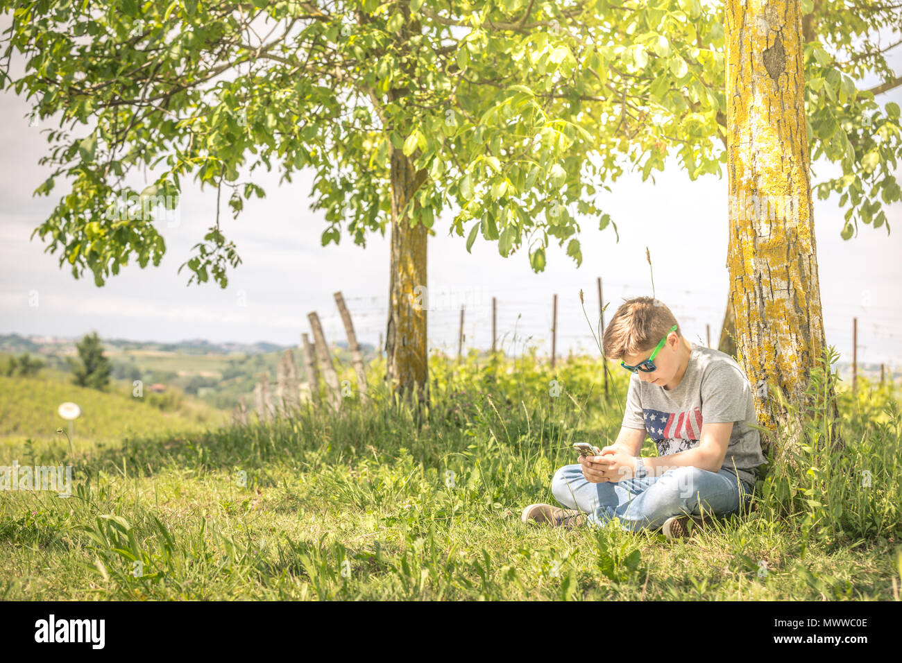 Boy sitting under a tree hi-res stock photography and images - Alamy