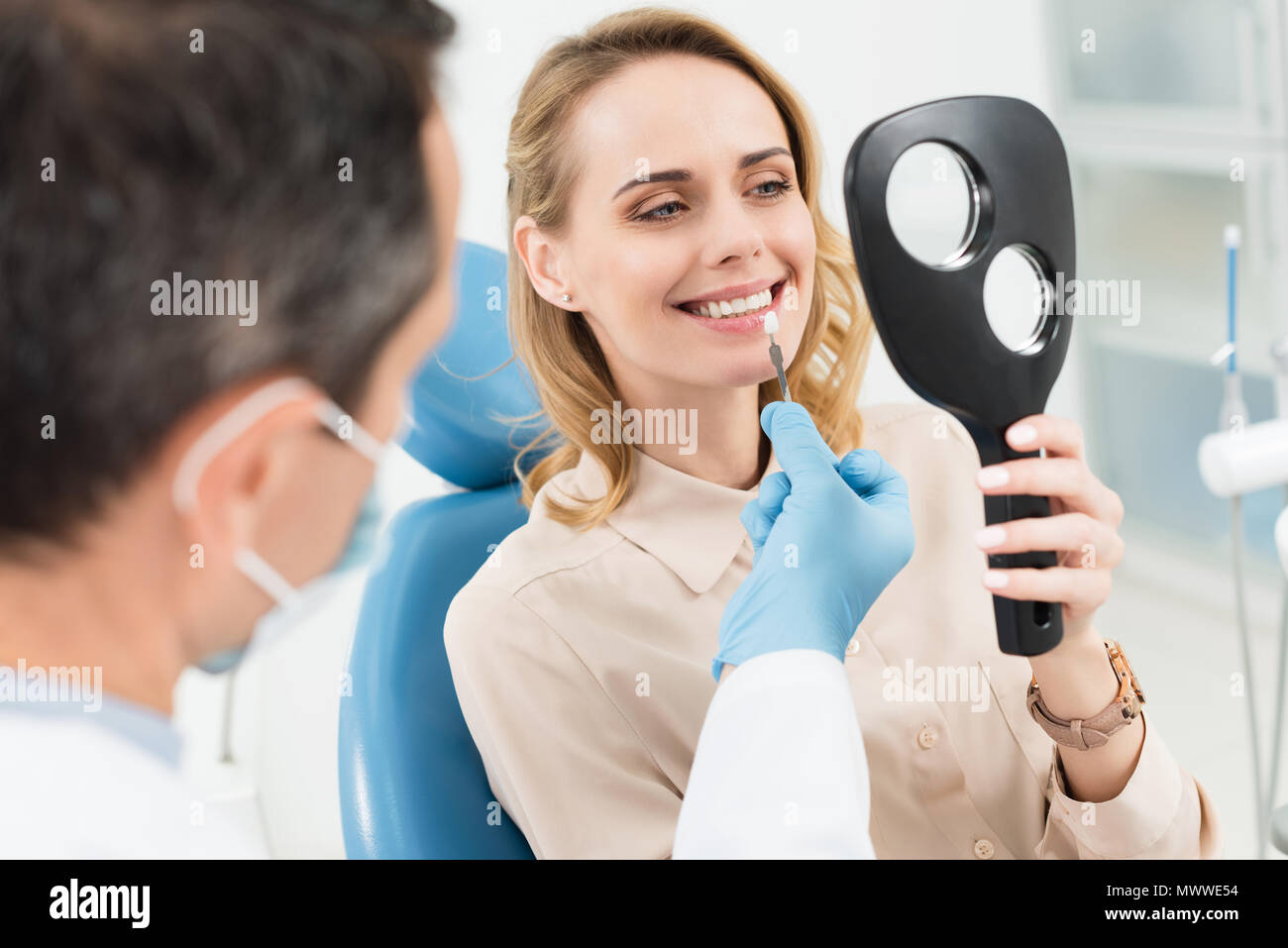 Female patient choosing tooth implant looking at mirror in modern ...
