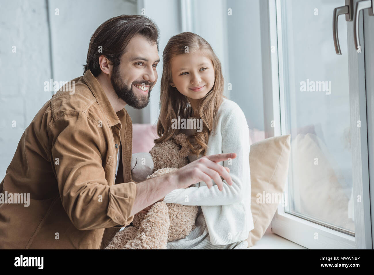 smiling father pointing on something to daughter at window Stock Photo ...