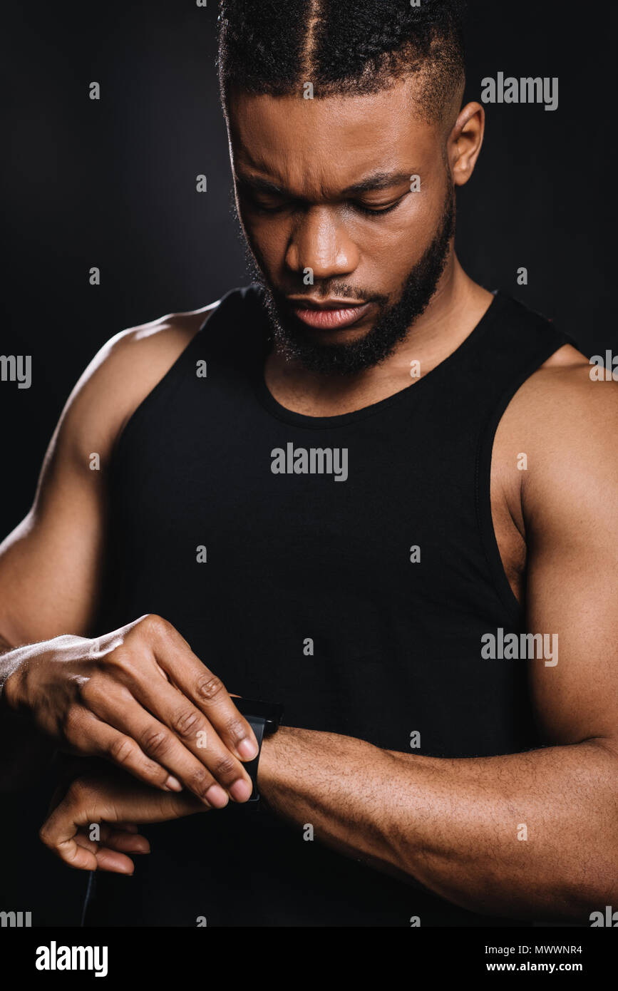 serious muscular african american man using smartwatch on black Stock ...