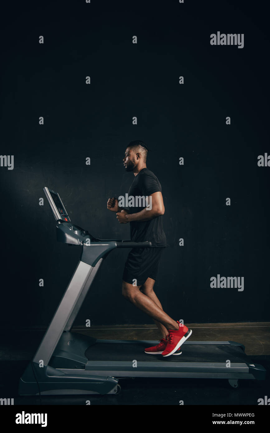 side view of young african american sportsman running on treadmill on ...