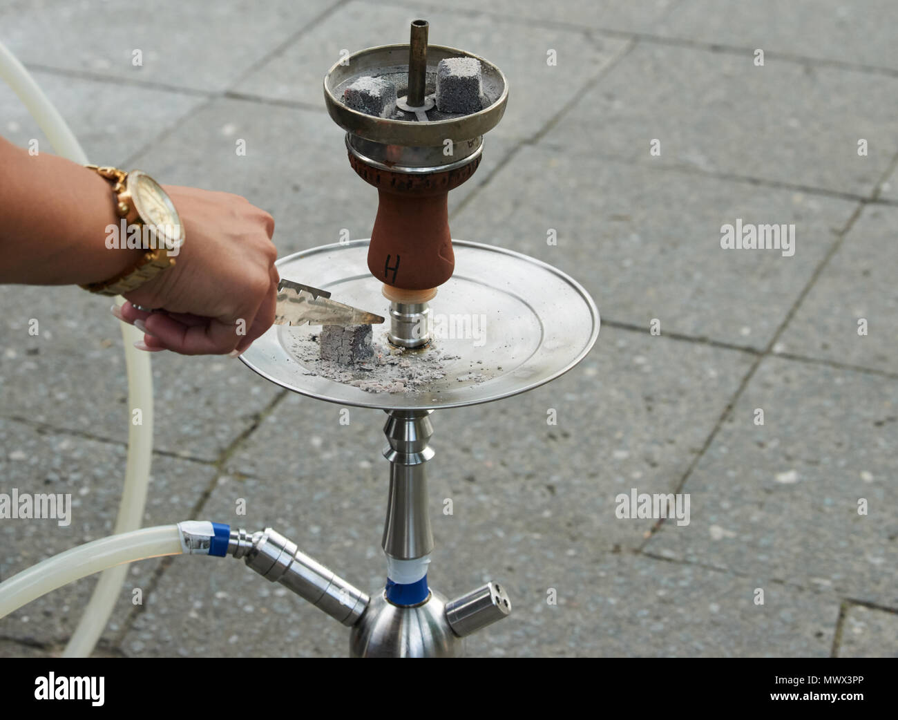 30 May 2018, Germany, Berlin: A guest at a shisha bar places a cube of ...