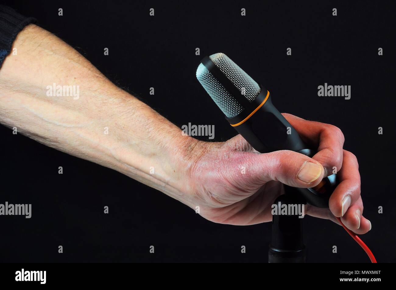 Male hand with microphone on black background Stock Photo - Alamy