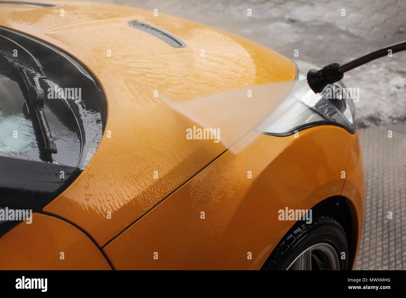 Yellow car front washed by water jet spray in carwash Stock Photo - Alamy