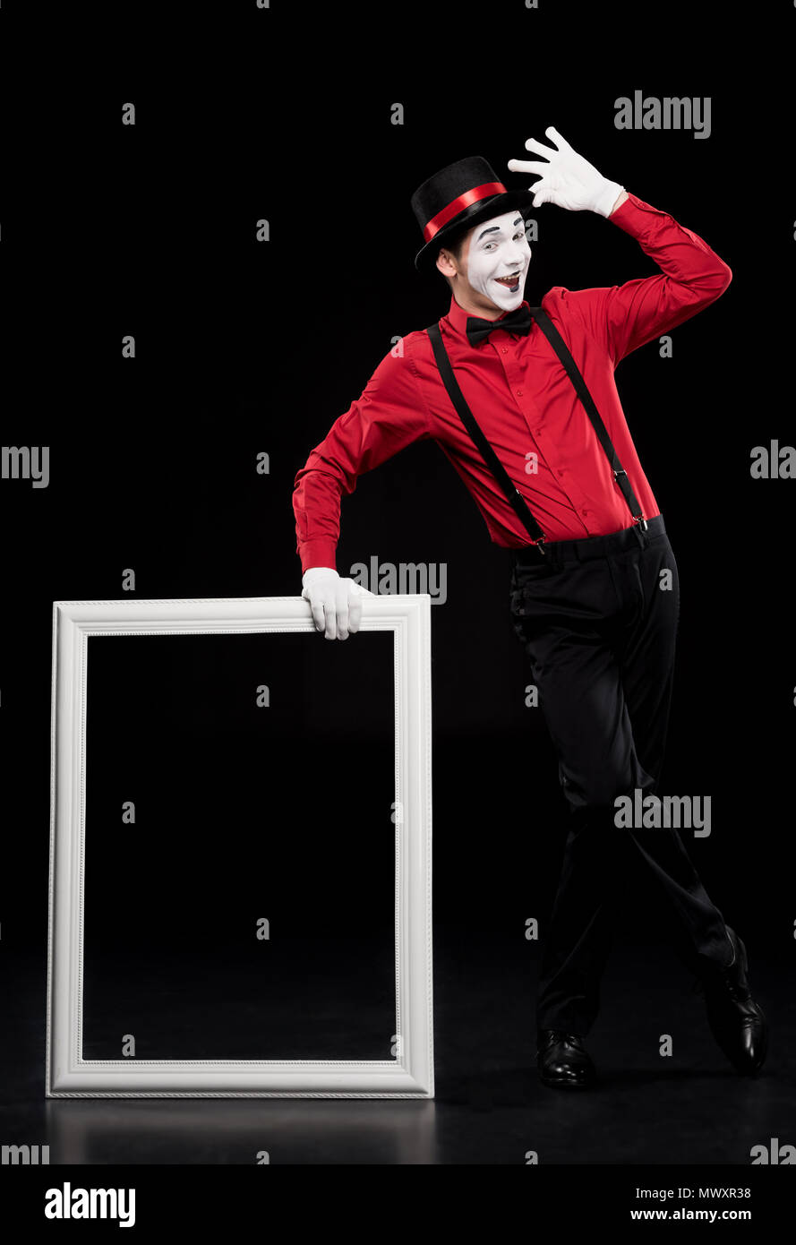happy mime leaning on frame and waving hand isolated on black Stock ...